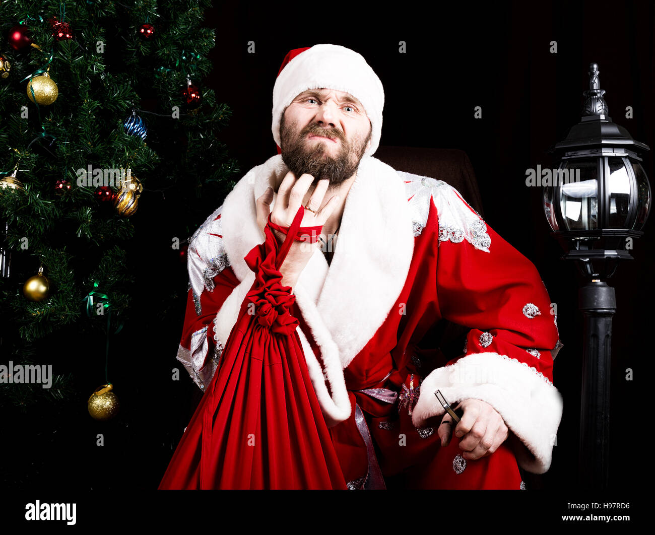 bad brutal Santa Claus holding the bag with gifts and scratching his ...