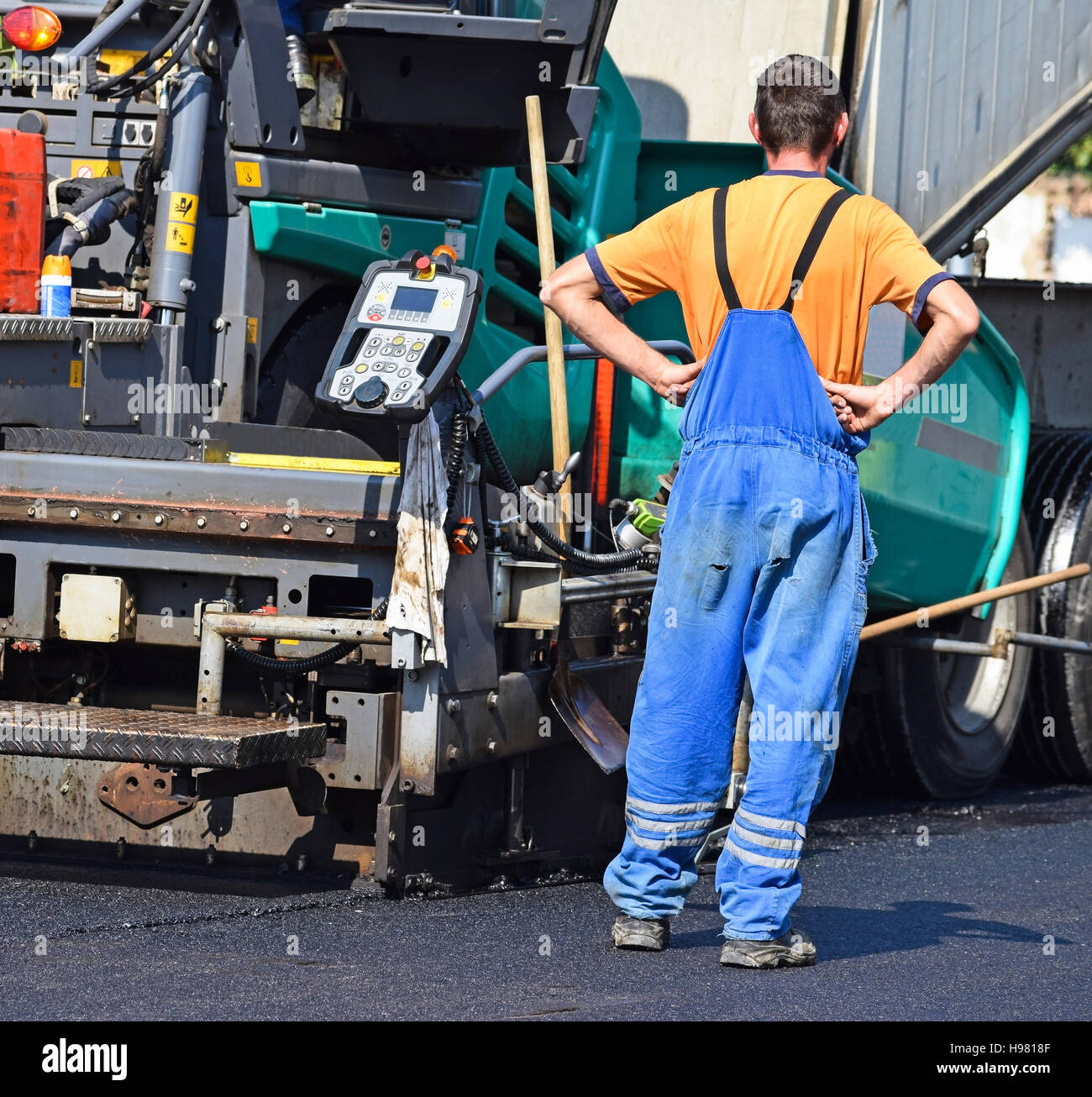 Construction worker next to an asphalt paving vehicle at the road ...