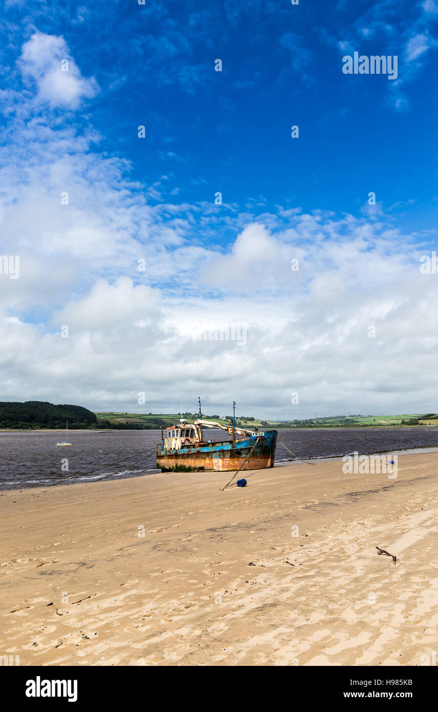 an old rusty boat on the beach of the River Tywi under a blue sky with ...