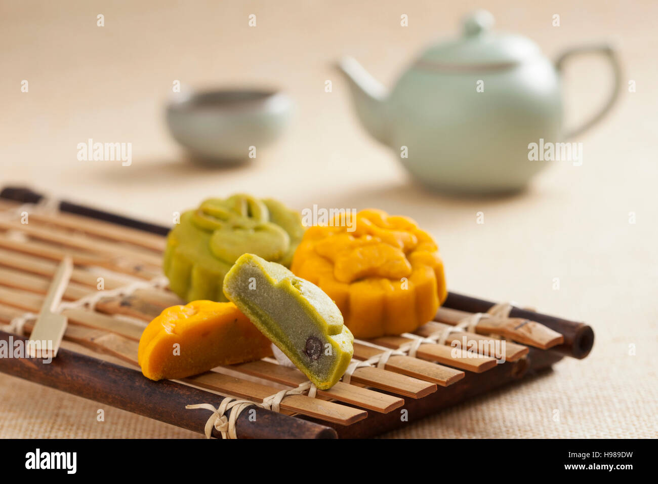 Two mooncakes, half cut showing inside with Chinese tea background ...