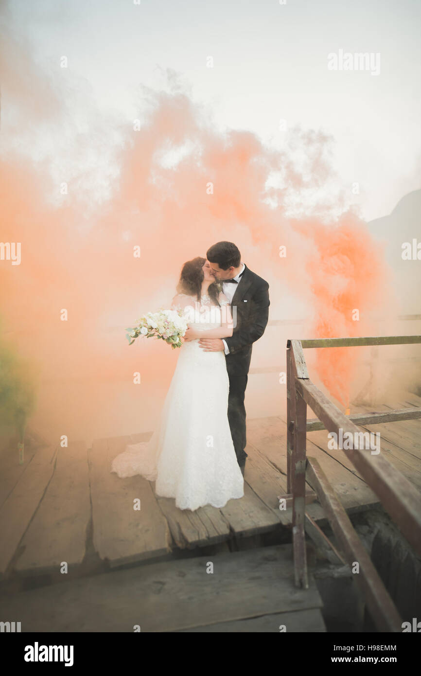 Wedding couple posing near rocks with colored smoke behind them Stock ...