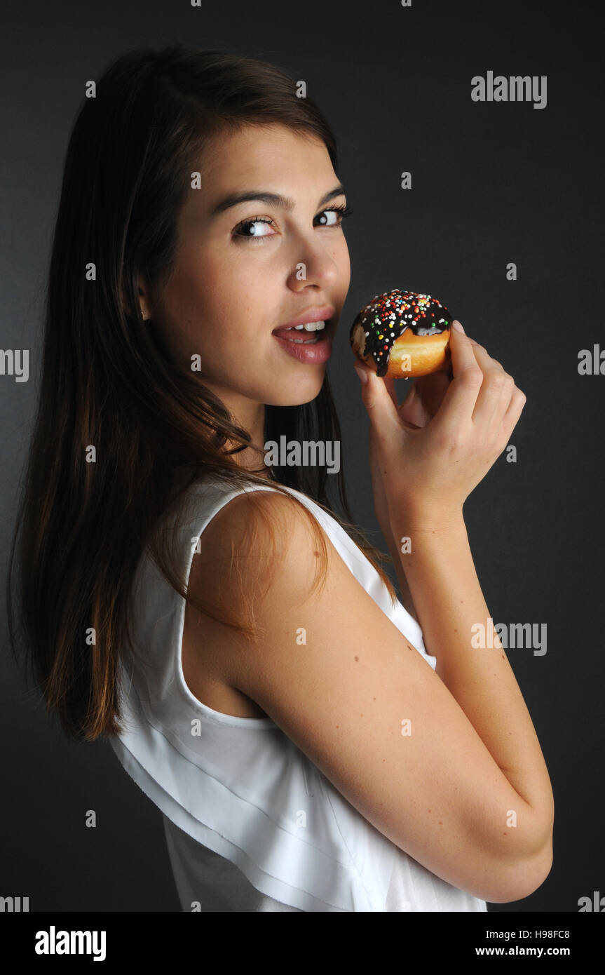 Beautiful woman eating chocolate donut Stock Photo - Alamy