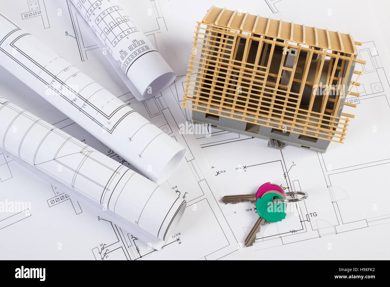 Home keys, small house under construction and rolls of diagrams on ...