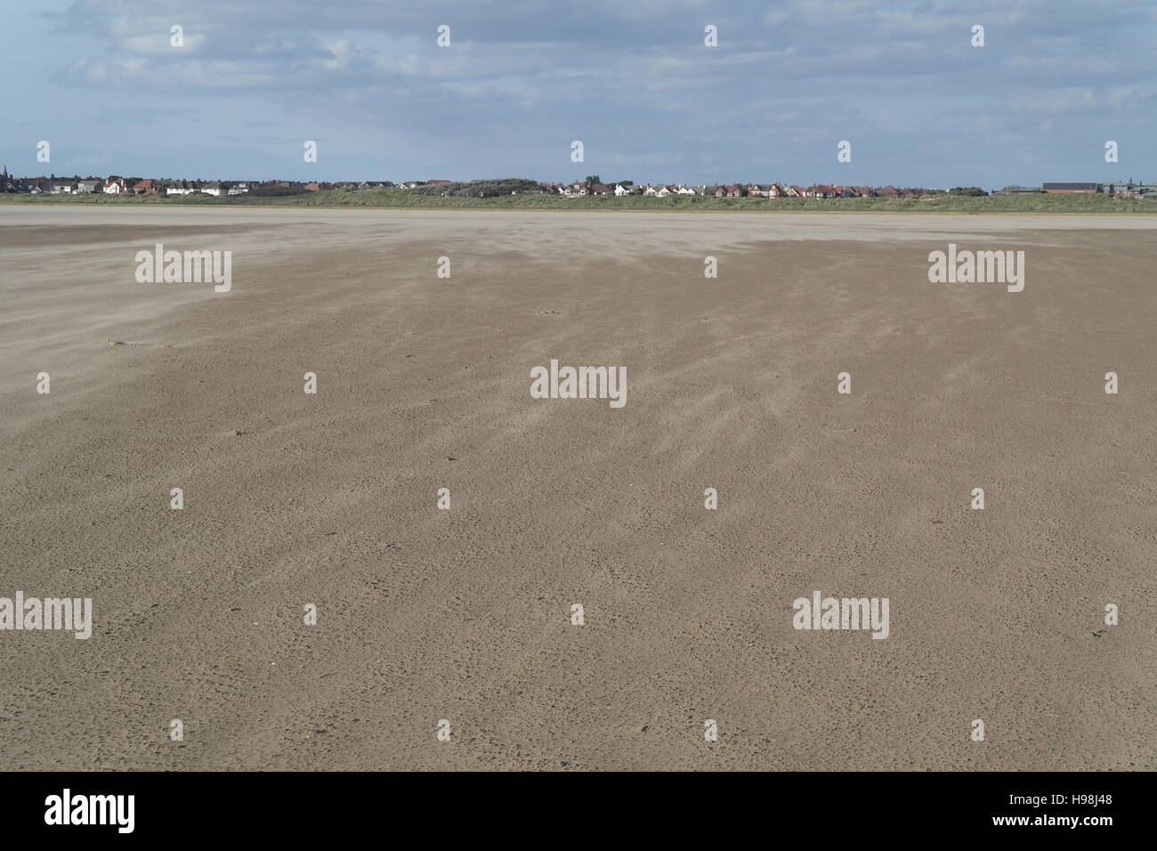 Sunny day grey clouds view sand blowing on a dry expanse of beach ...