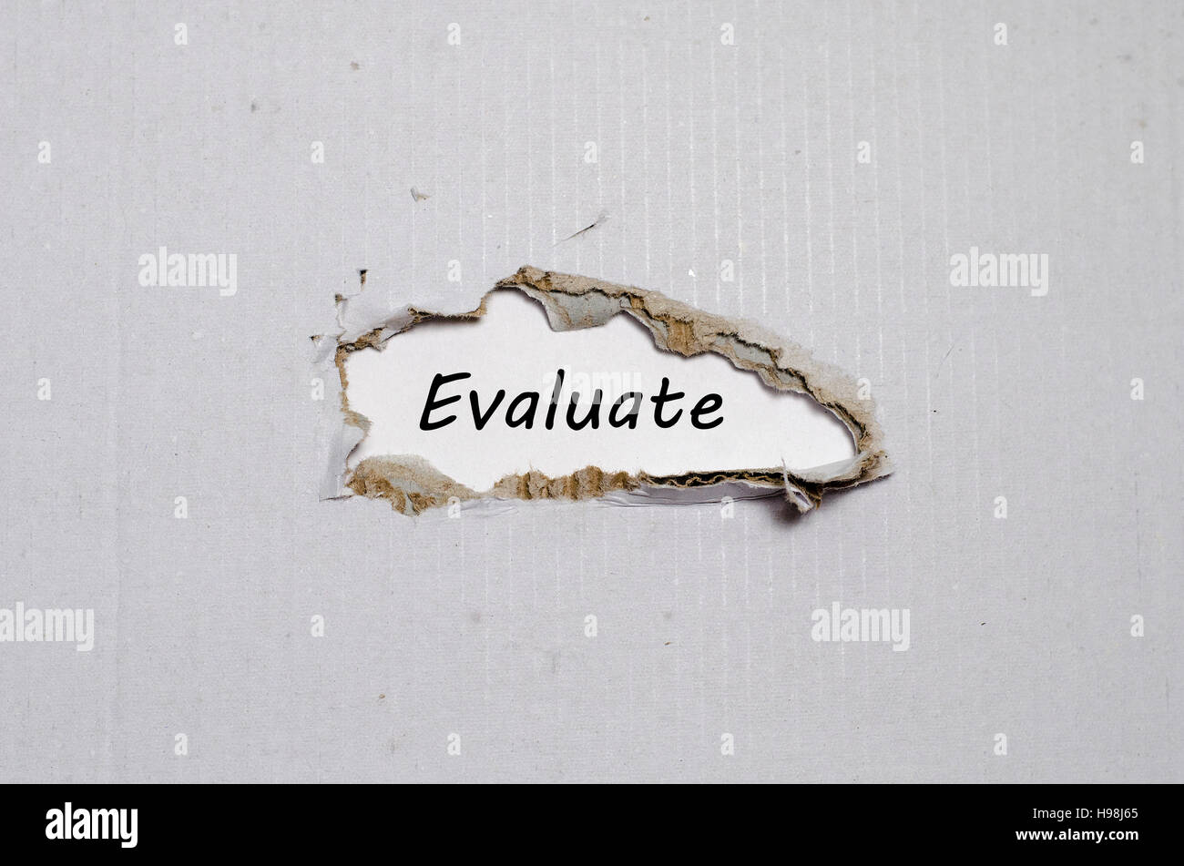 The word evaluate appearing behind torn paper Stock Photo - Alamy