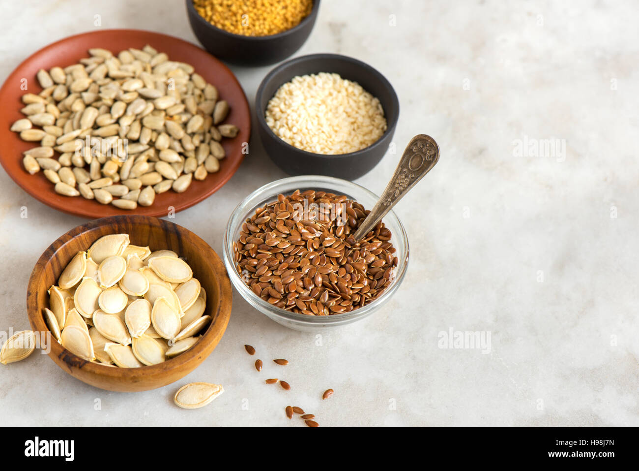 Assorted oil seeds (flax, sesame, pumpkin, sunflower, mustard) on stone ...
