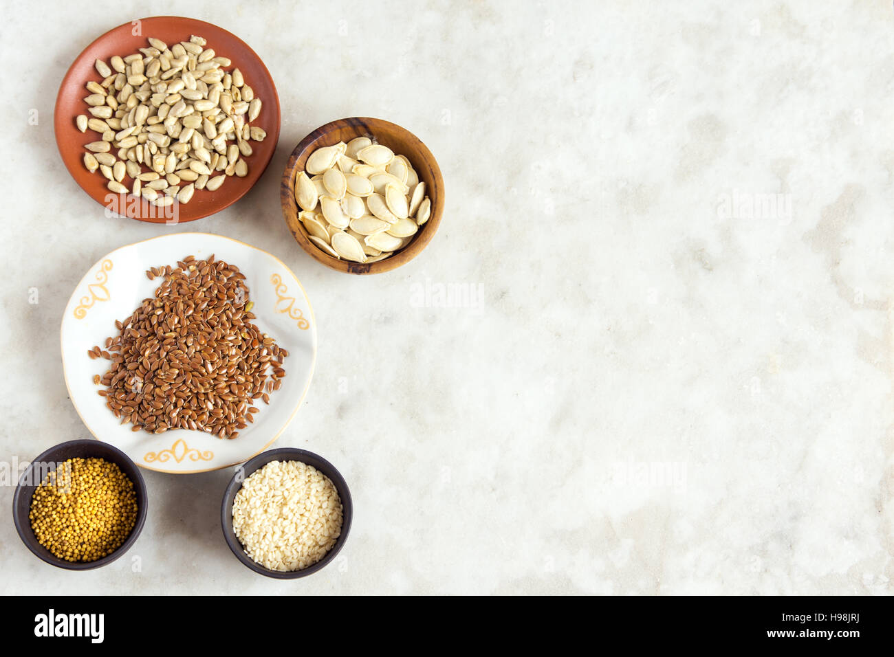 Assorted oil seeds (flax, sesame, pumpkin, sunflower, mustard) on stone ...