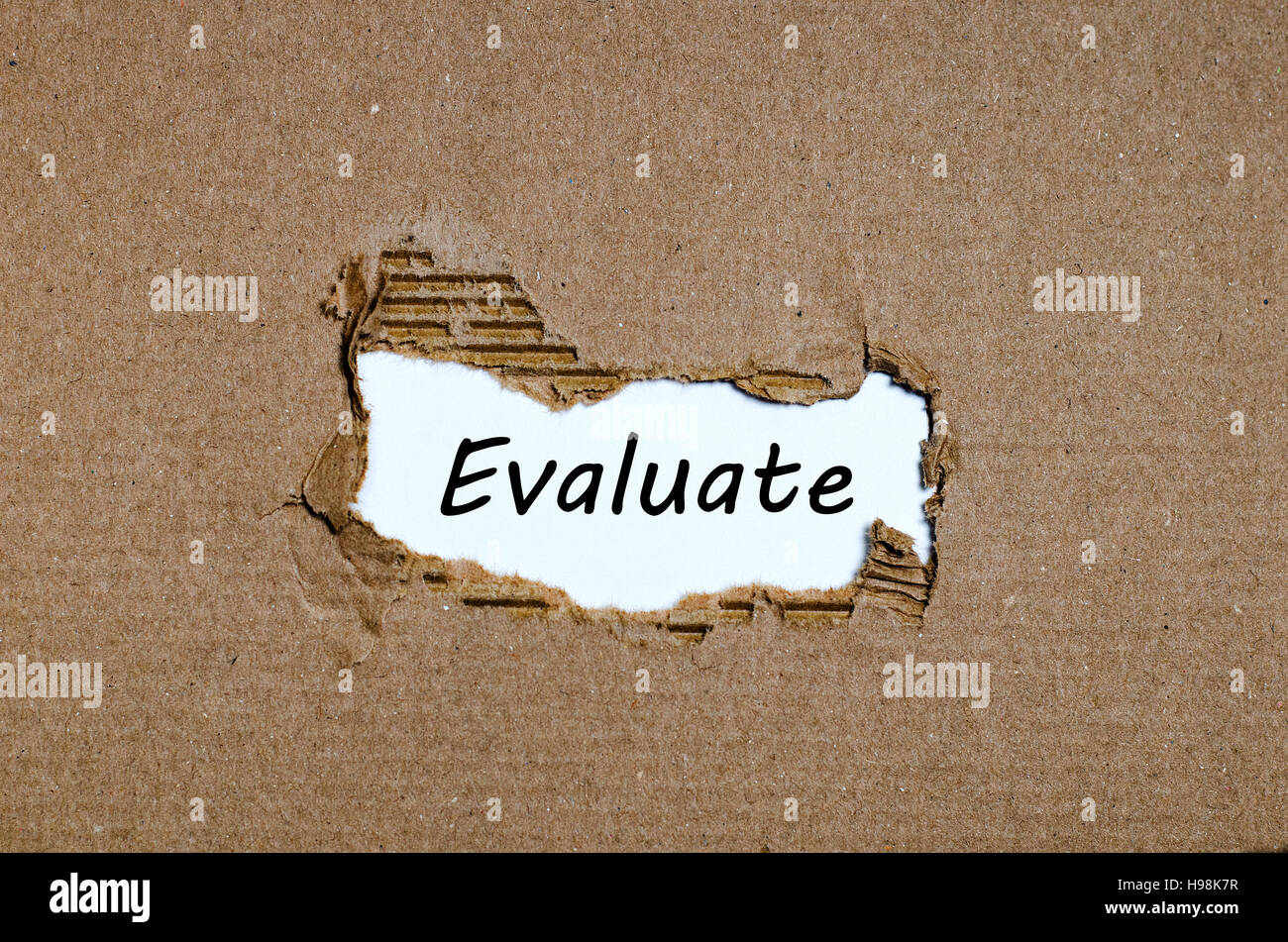 The word evaluate appearing behind torn paper Stock Photo - Alamy