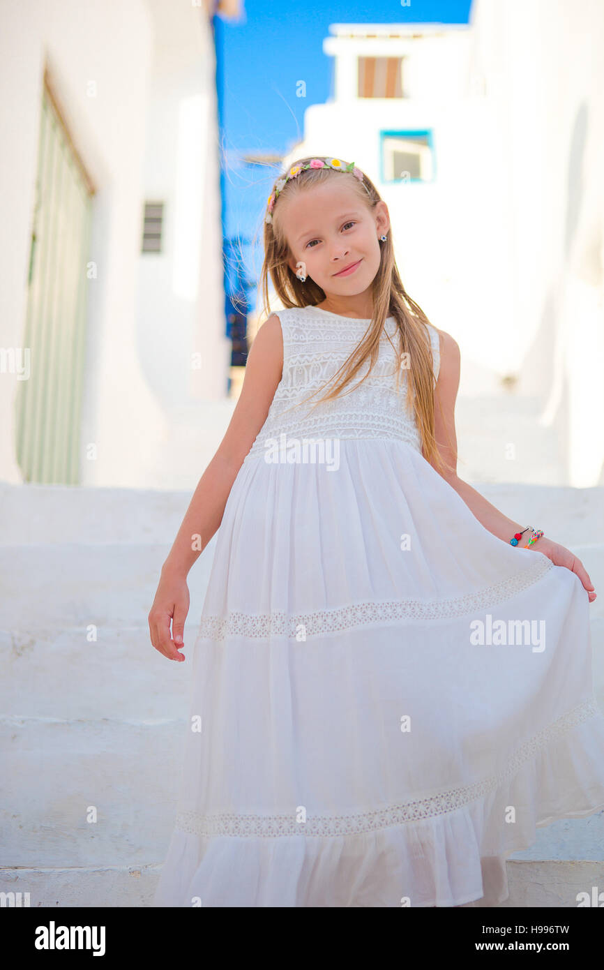 Adorable girl outdoors in greek village. Kid at street of typical greek ...