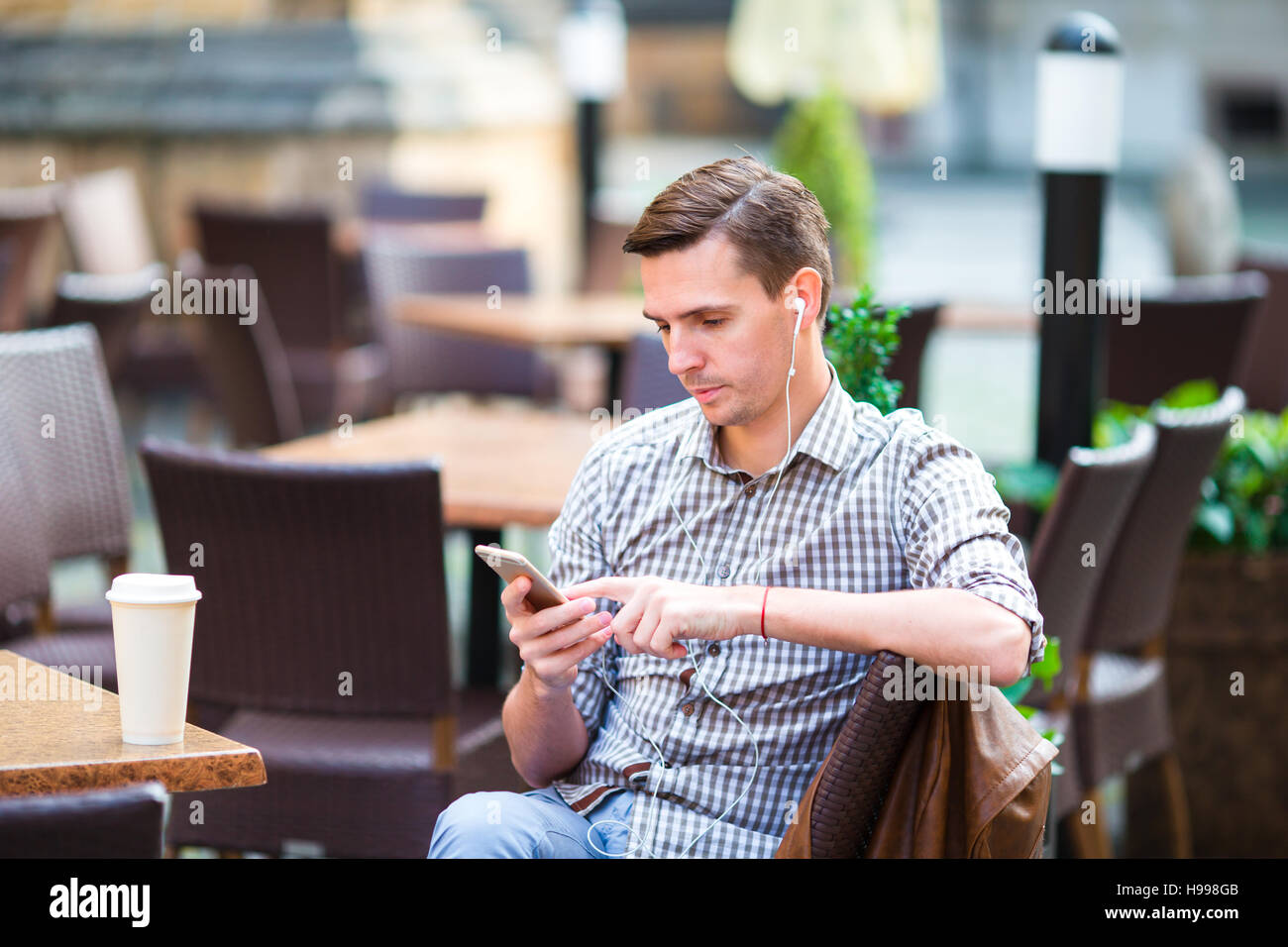 Caucasian boy is holding cellphone outdoors on the street. Man using ...