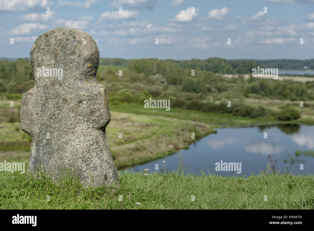 ancient stone religious cross on a hill in the background of the river ...