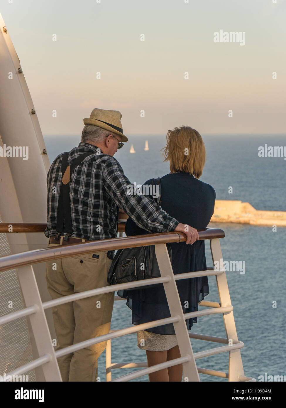 Two people standing on the deck of a cruise ship, looking out to sea ...
