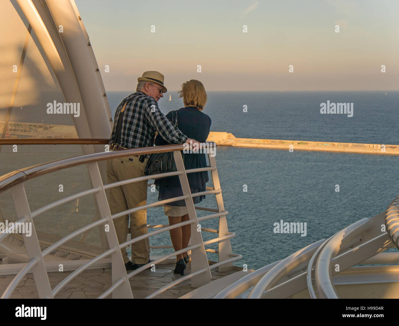 Two people standing on the deck of a cruise ship, looking out to sea ...