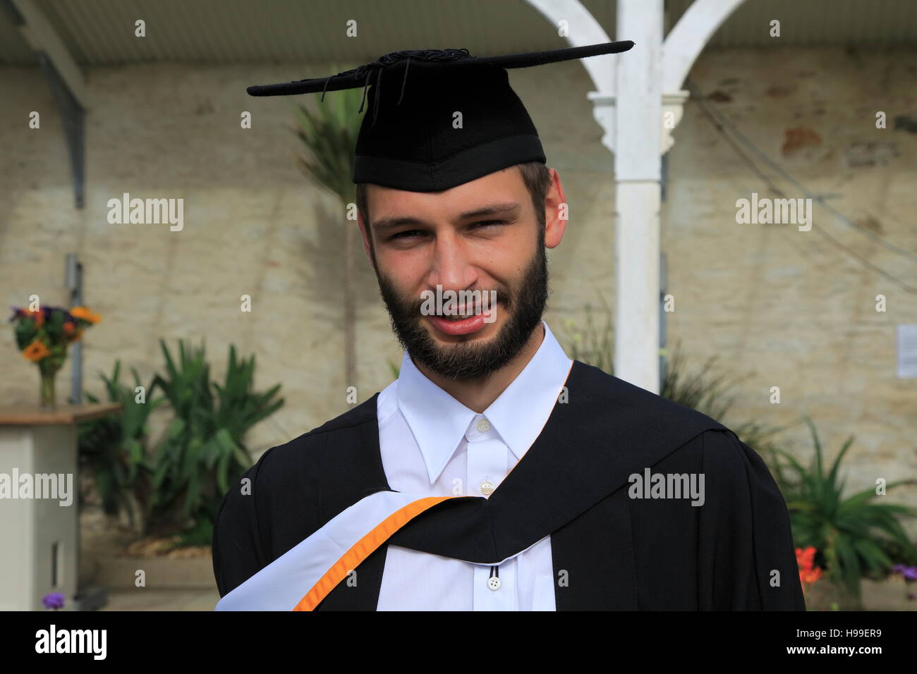 Portrait of male graduate wearing academic gown and mortarboard ...