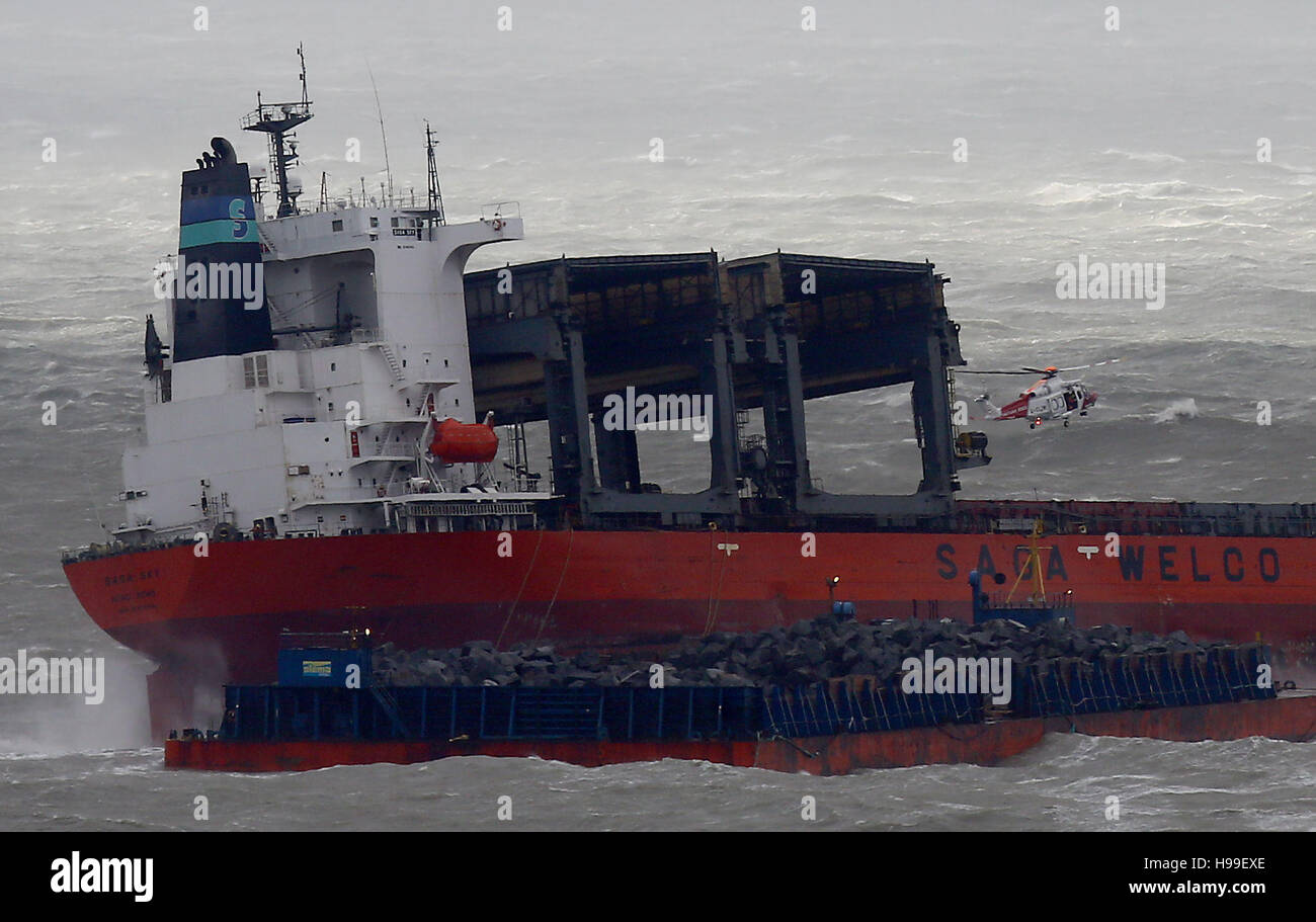 A coast guard helicopter attends the scene as crew members are ...