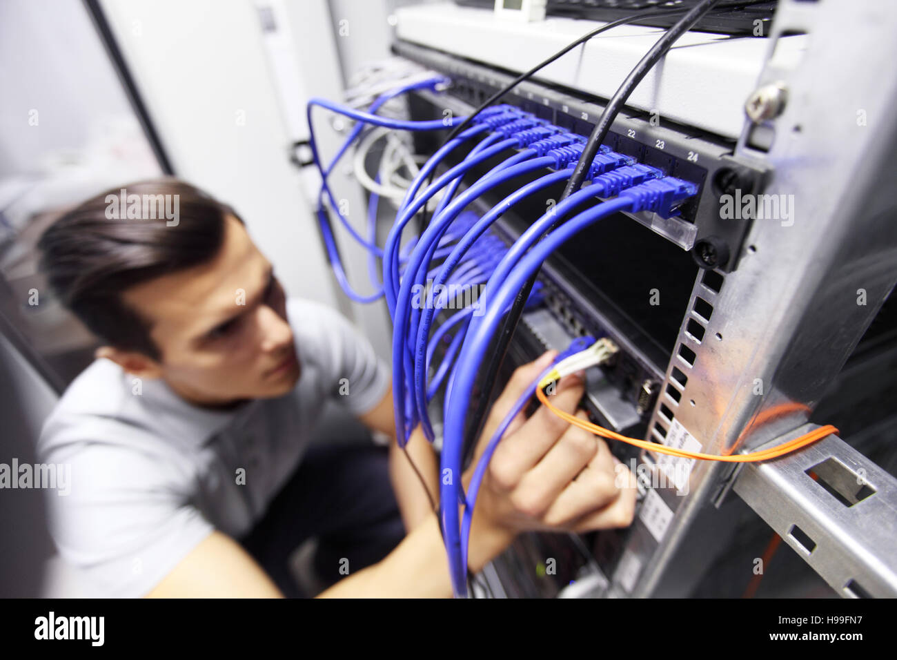 Man connecting network cables to switches Stock Photo - Alamy