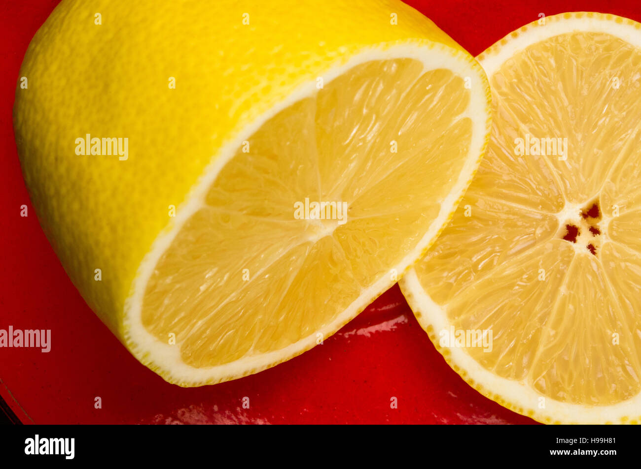 Sliced yellow lemon in red saucer on black background Stock Photo - Alamy