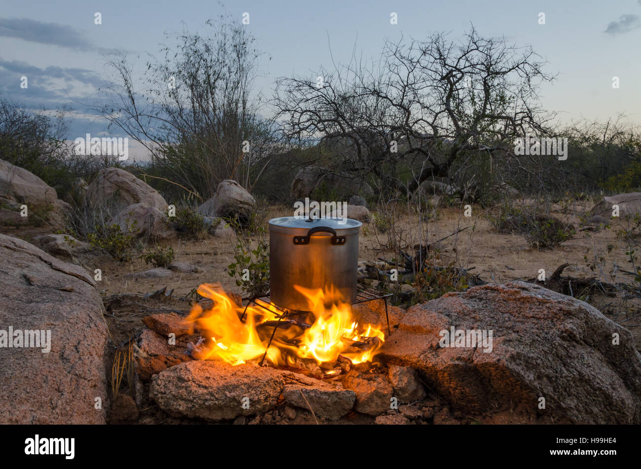 Aluminium pot standing on foldable grill being heated over outdoor camp ...