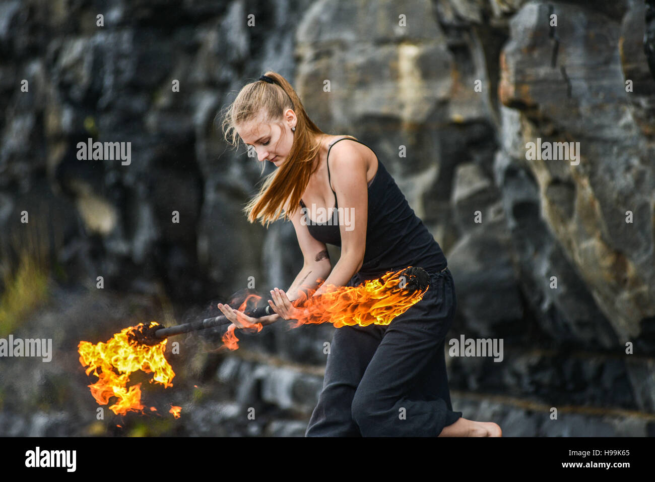 Girl in a black suit with flaming torches Stock Photo - Alamy