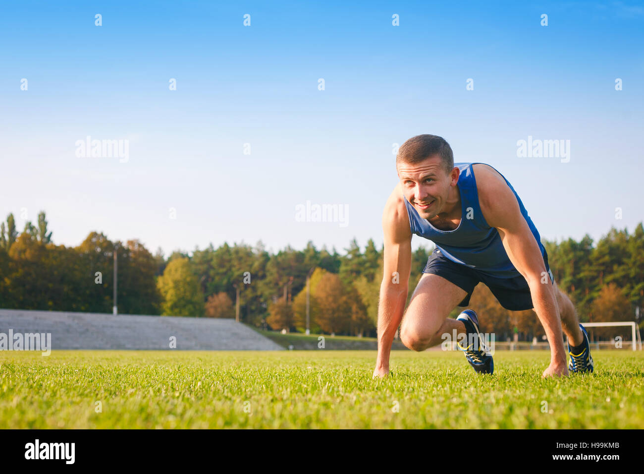 Man in low start position on old stadium. Athlete in starting position ...