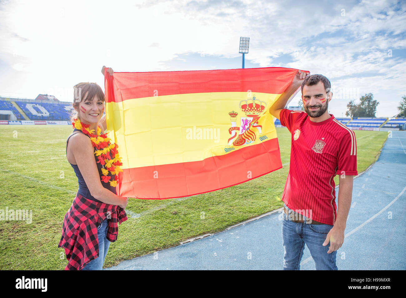 Young couple with face paint waving Spanish flag Stock Photo - Alamy