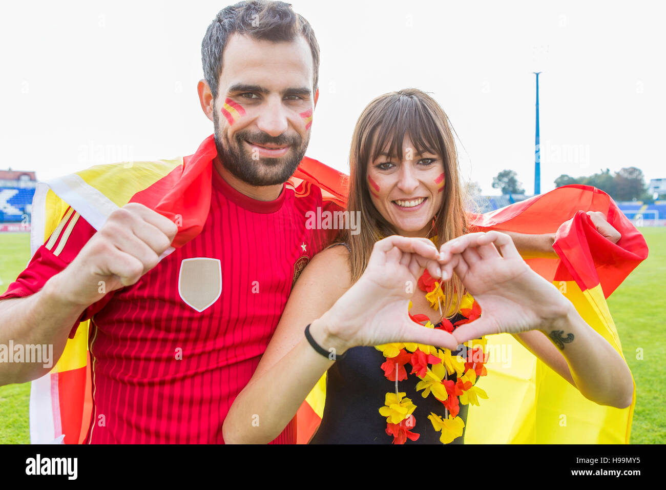 Young couple with face paint waving Spanish flag Stock Photo - Alamy