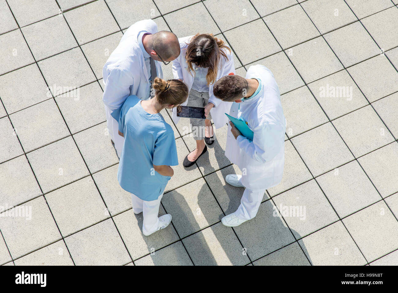 Doctors stand in circle looking at digital tablet Stock Photo - Alamy