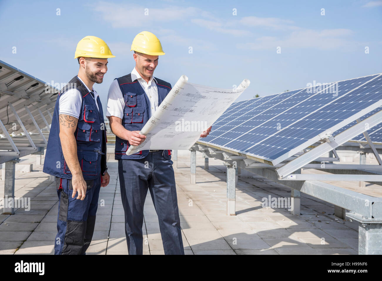 Construction workers next to solar panels looking at blueprint Stock ...