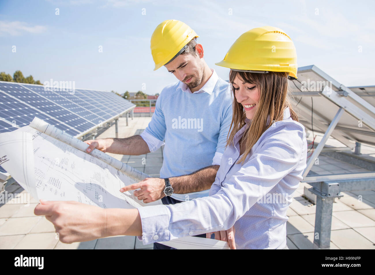Two architects with blueprint at solar power station Stock Photo - Alamy