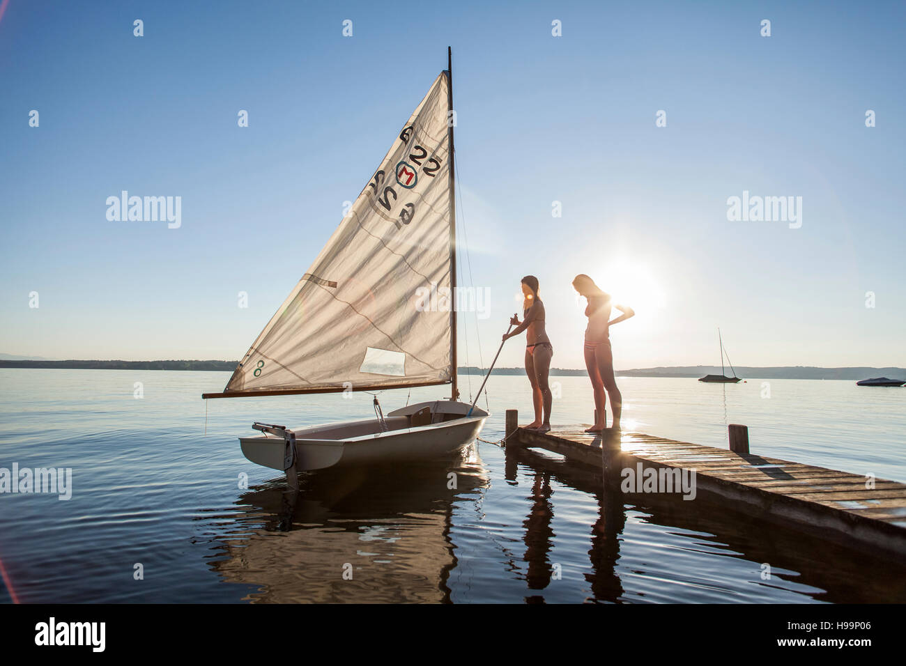 Two young women standing by sailboat Stock Photo - Alamy