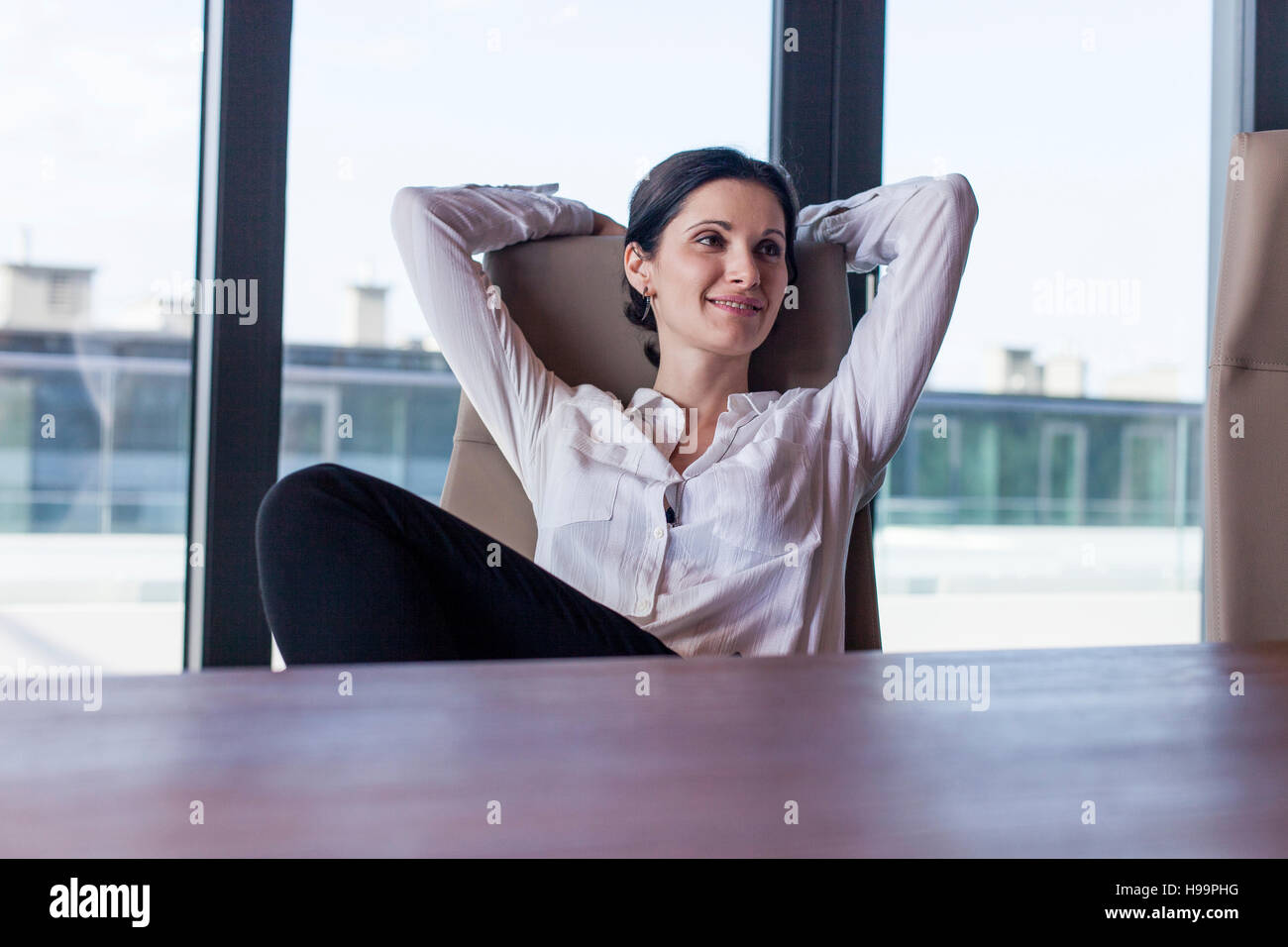 Businesswoman in office leaning back Stock Photo - Alamy
