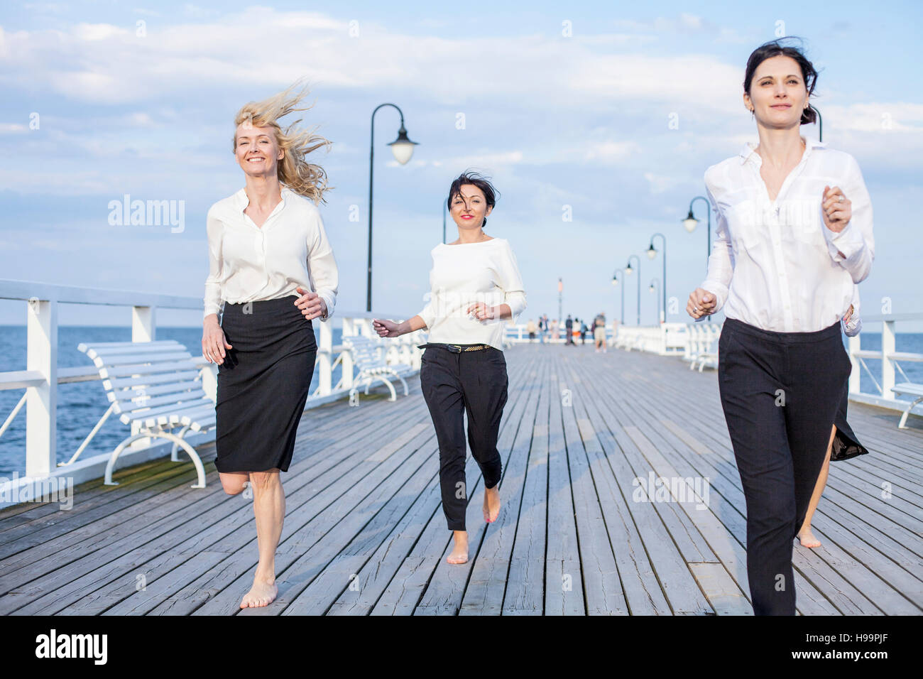 Group of businesswomen running along jetty Stock Photo - Alamy