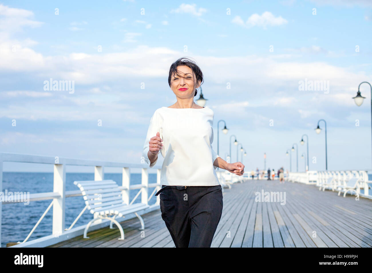 Businesswomen running along jetty Stock Photo - Alamy