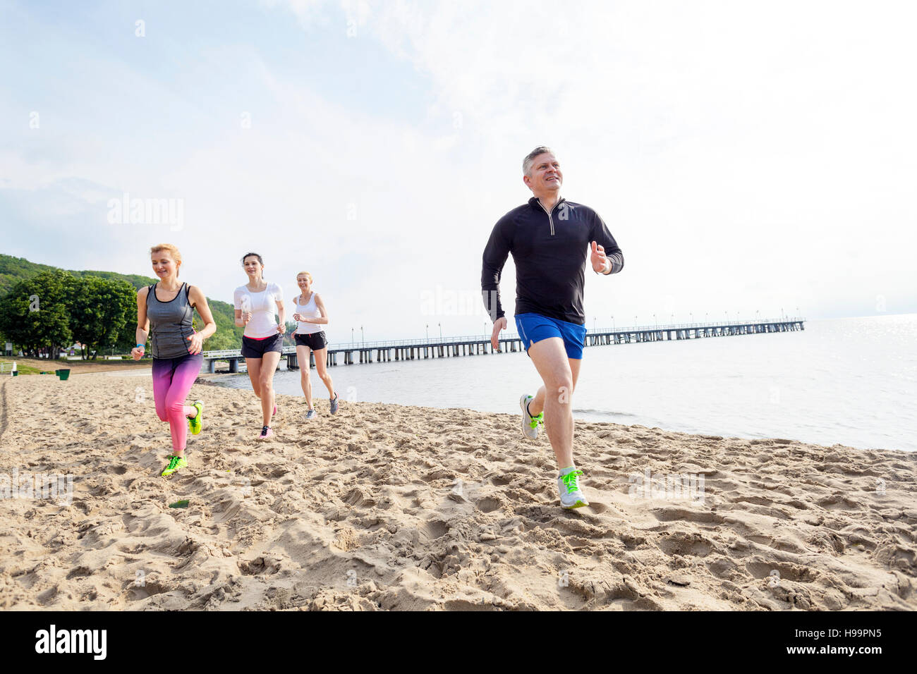 Group of friends jogging on beach Stock Photo - Alamy