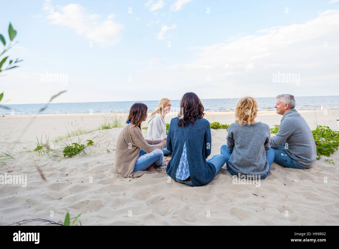 Group of friends sitting on sandy beach Stock Photo - Alamy