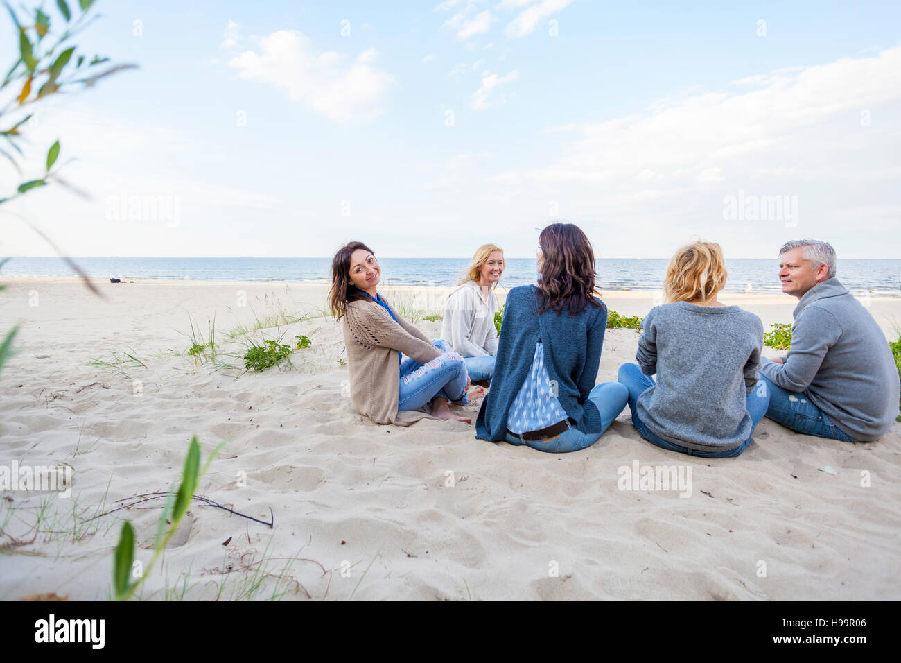 Group of friends sitting on sandy beach Stock Photo - Alamy