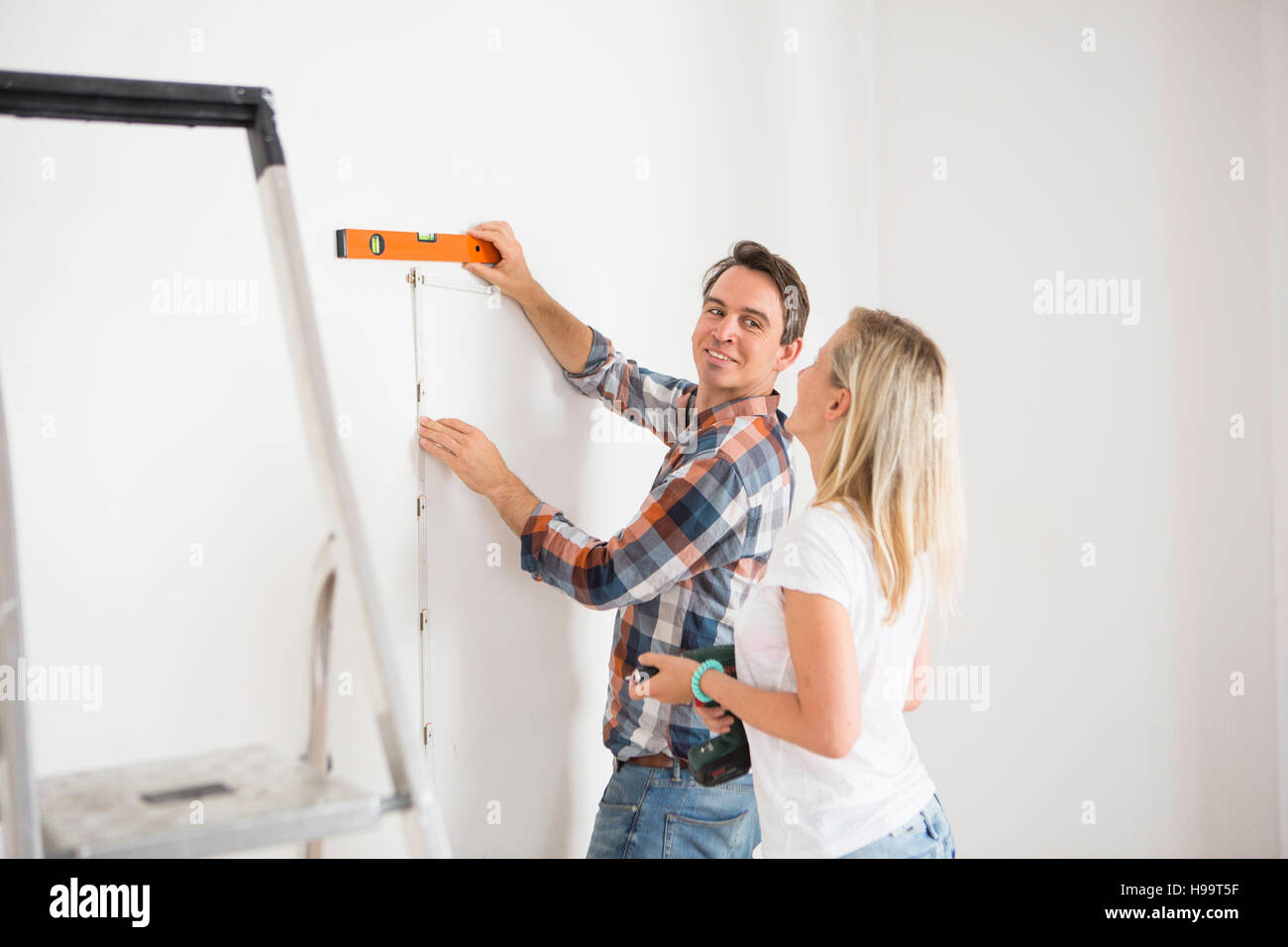 Young couple using water level and folding ruler Stock Photo - Alamy