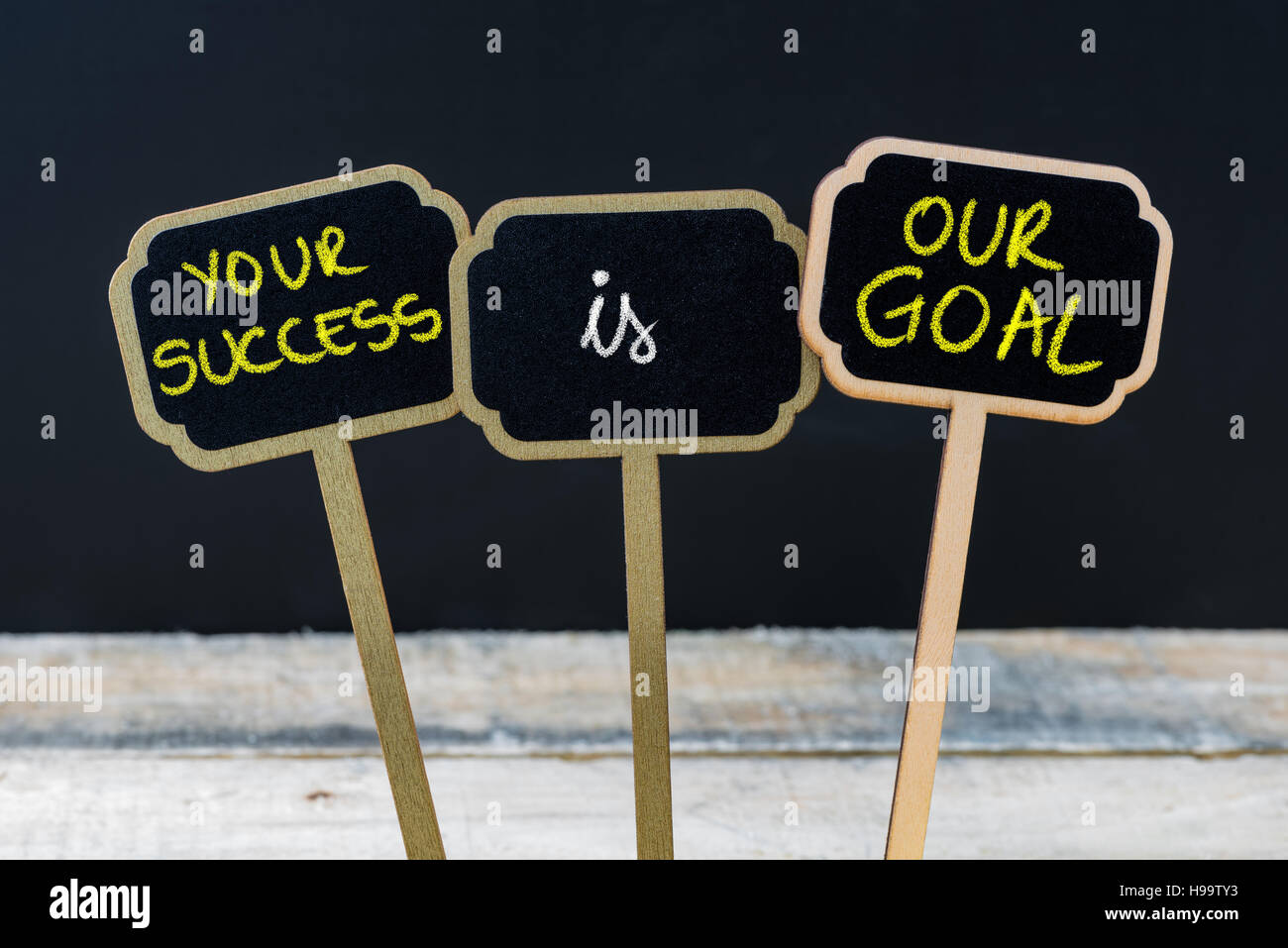 Concept message YOUR SUCCESS IS OUR GOAL written with chalk on wooden mini blackboard labels ...