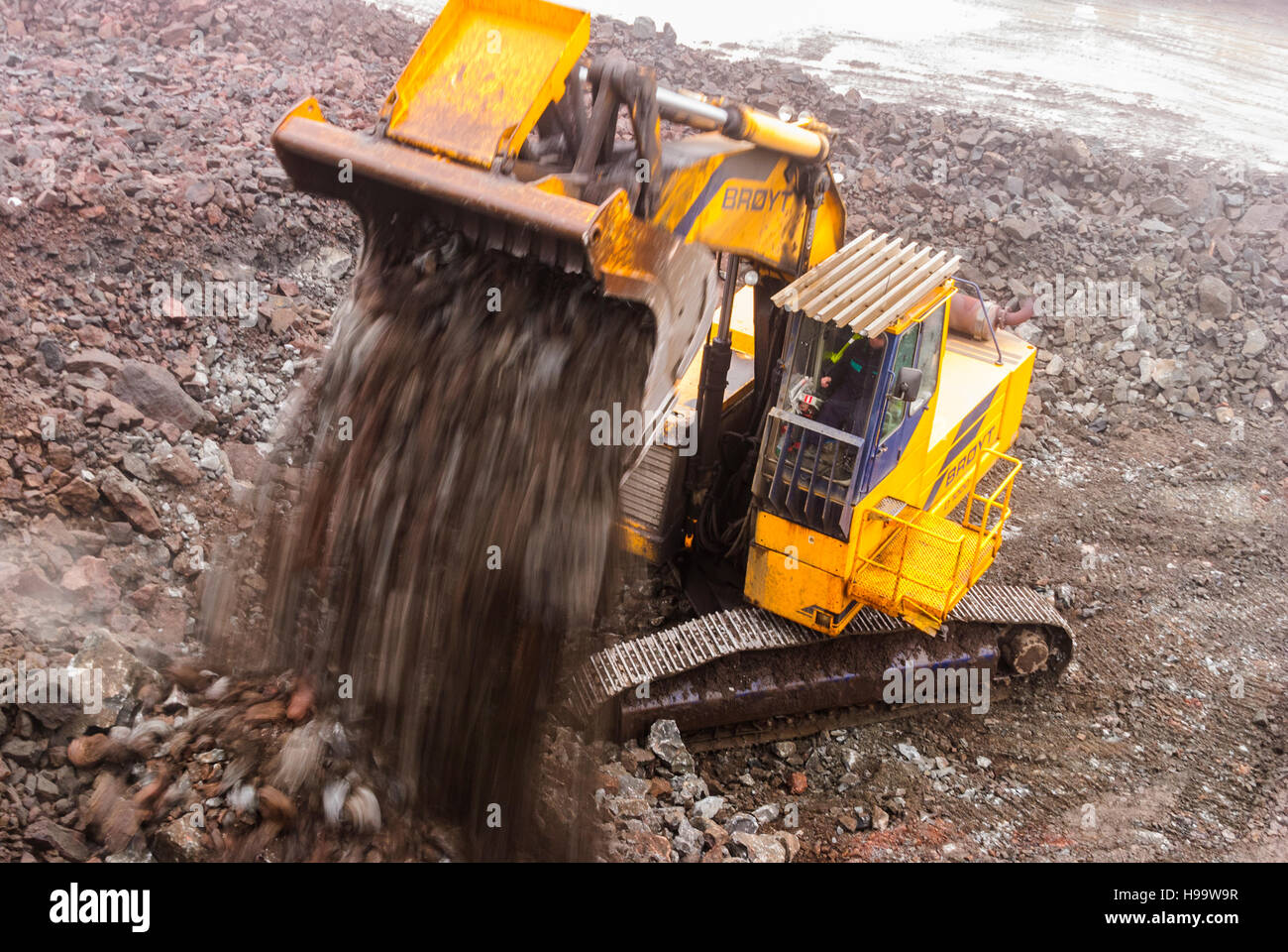 A Broyt tracked loader dumps a bucket of rocks in a quarry in heavy ...