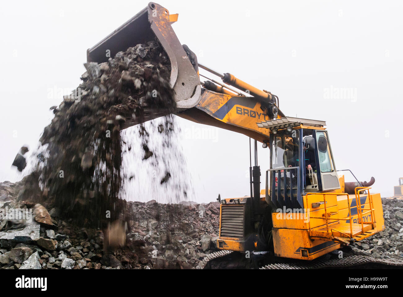 A Broyt tracked loader dumps a bucket of rocks in a quarry in heavy ...
