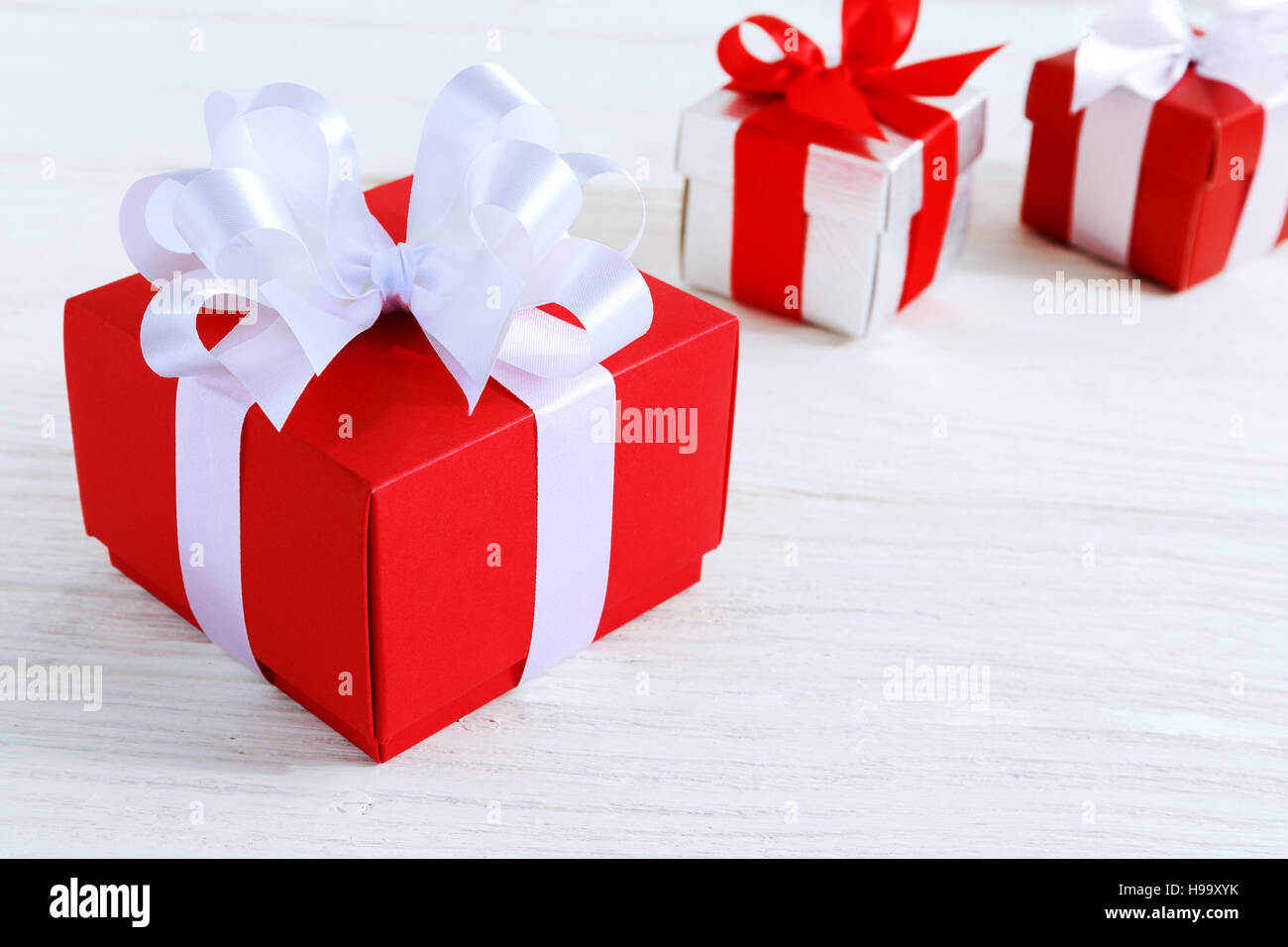 Red gift box with white ribbon on white wood table Stock Photo - Alamy