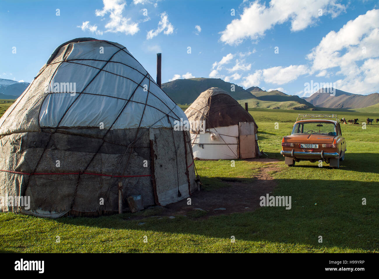 An old car sits outside a camp of yurts in the jailoo, or summer ...