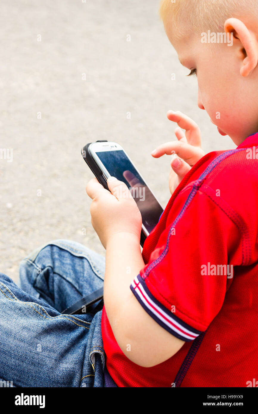 Little boy child kid playing games on smartphone mobile phone outdoor ...