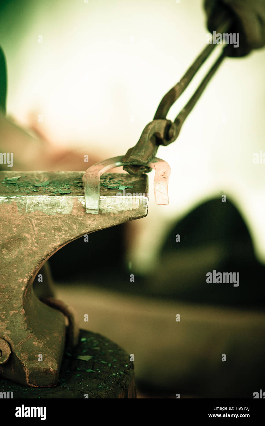 Making decorative element in the smithy on the anvil. Hammering glowing ...