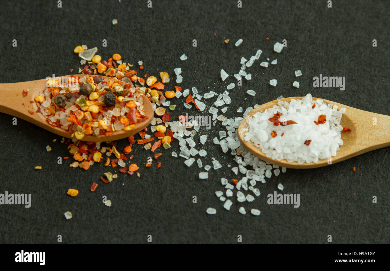 Two wooden spoons with spices and salt on black background Stock Photo ...
