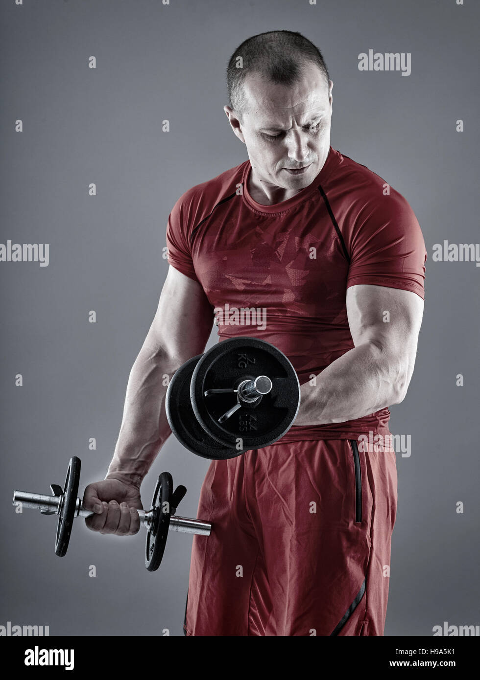 Fitness man doing biceps curl with dumbbells on gray background Stock ...