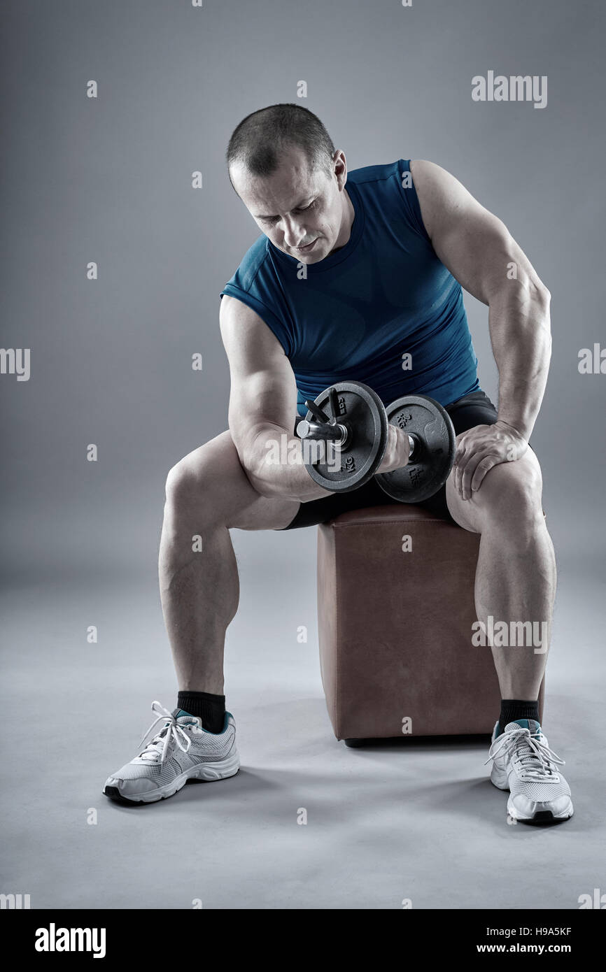 Fitness man doing biceps curl with dumbbells on gray background Stock ...