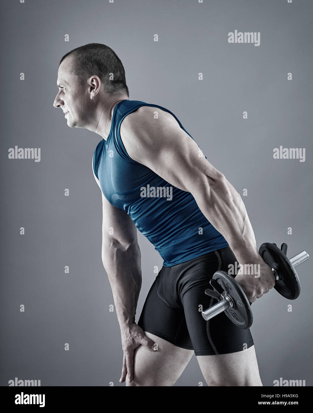Fitness man doing triceps workout with dumbbells on gray background ...