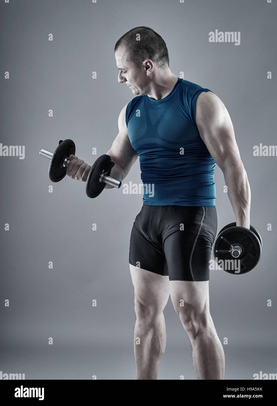 Fitness man doing biceps curl with dumbbells on gray background Stock ...