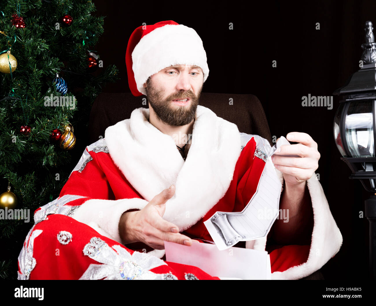bad brutal Santa Claus discontentedly reads letter with the wishes, on ...